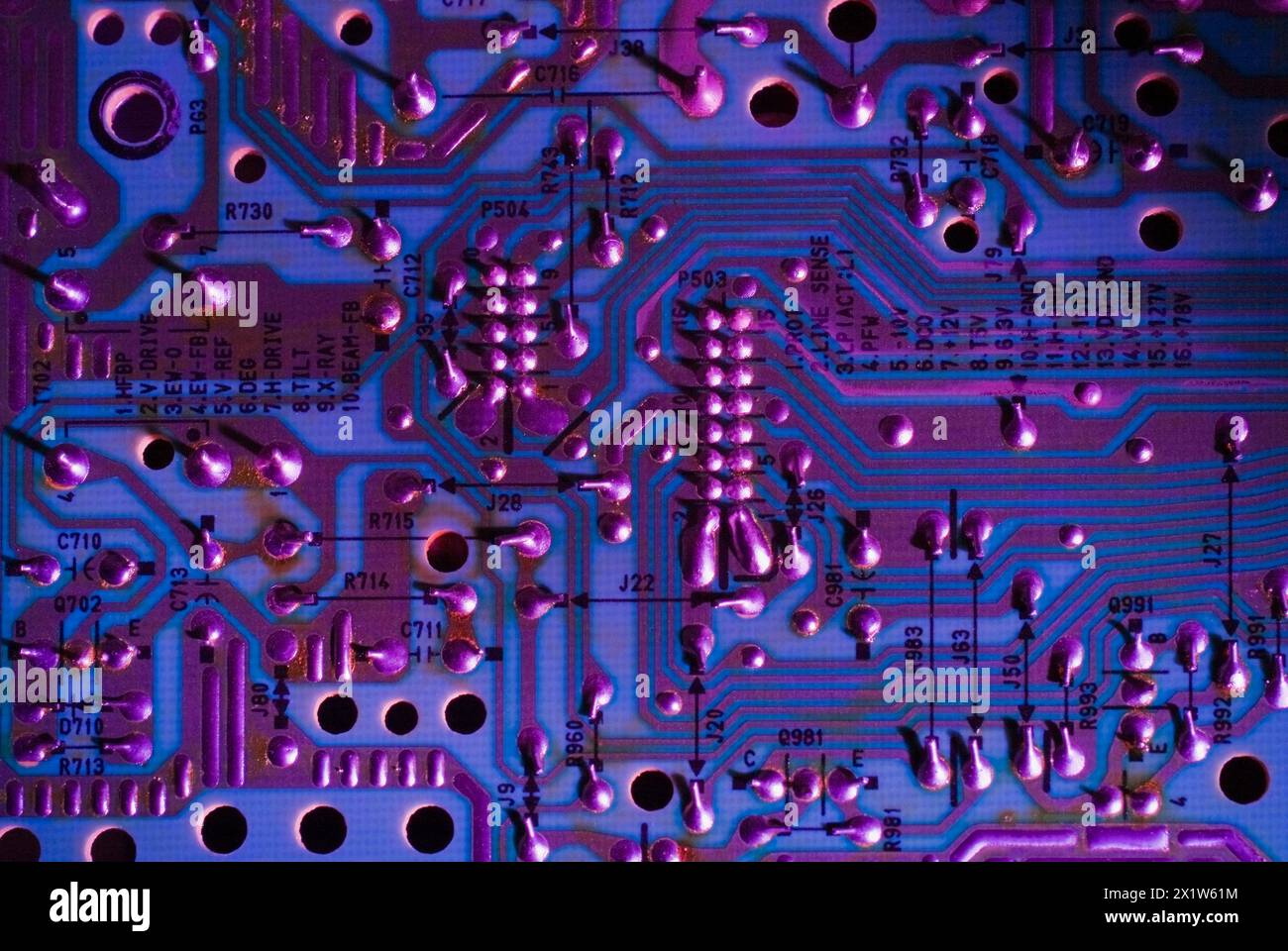 Close-up of purple and blue lighted electronic computer circuit board with silver solder points ...