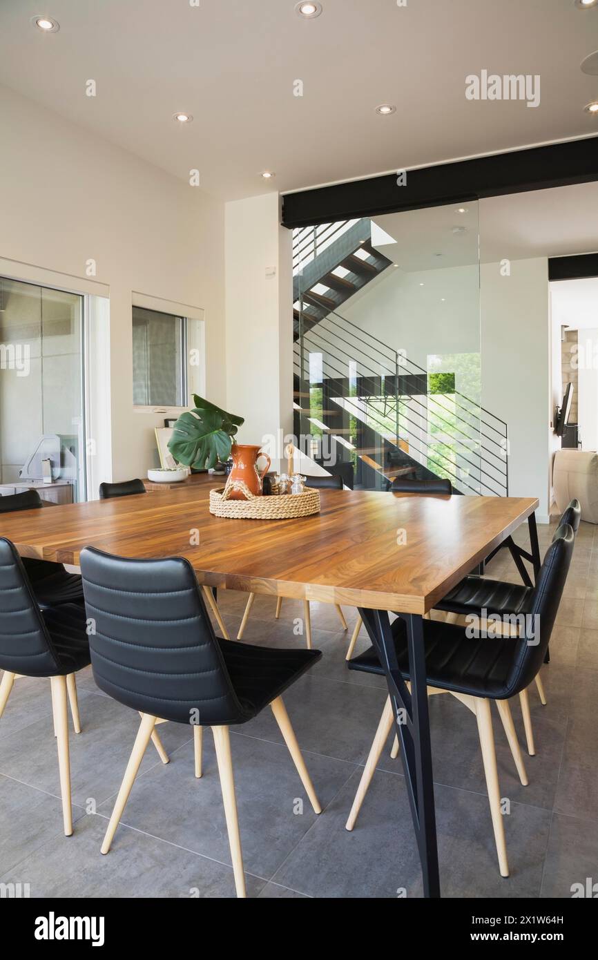 American walnut wood dining table and black leather sitting chairs with ...