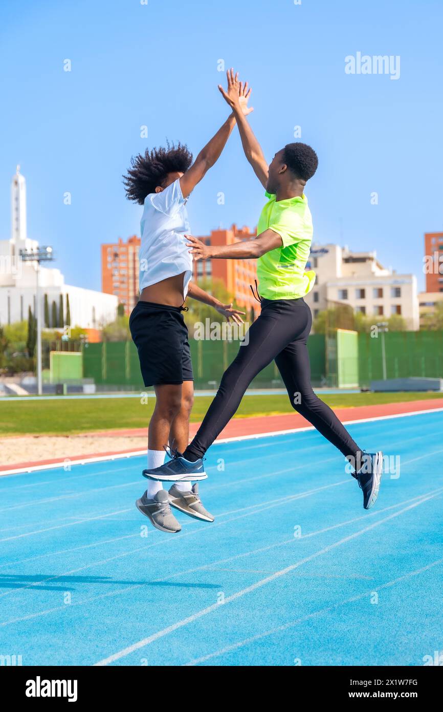 Vertical photo of two african american young friends jumping ...