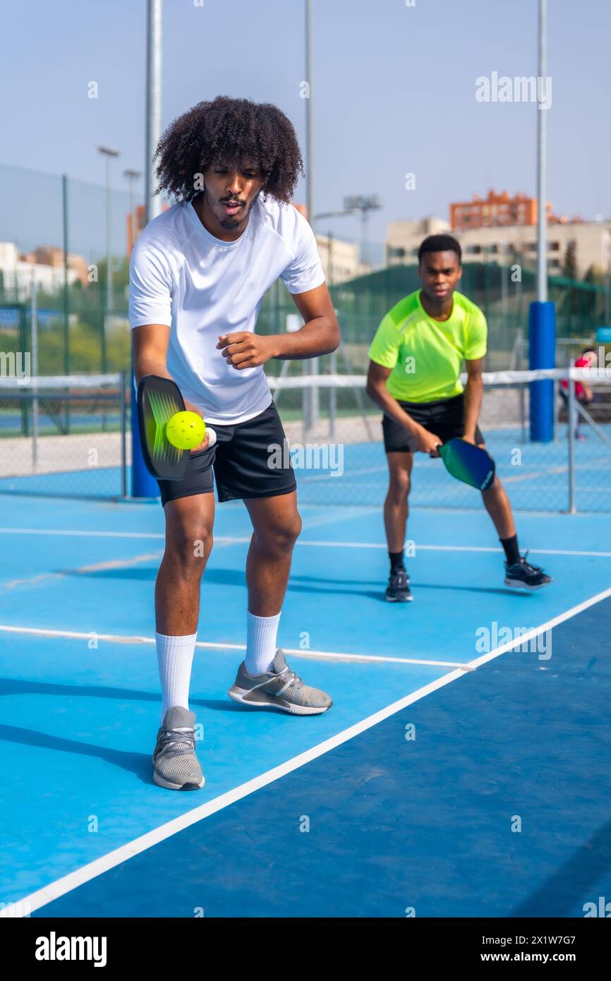 Vertical full length photo of an african sportive man serving ball ...