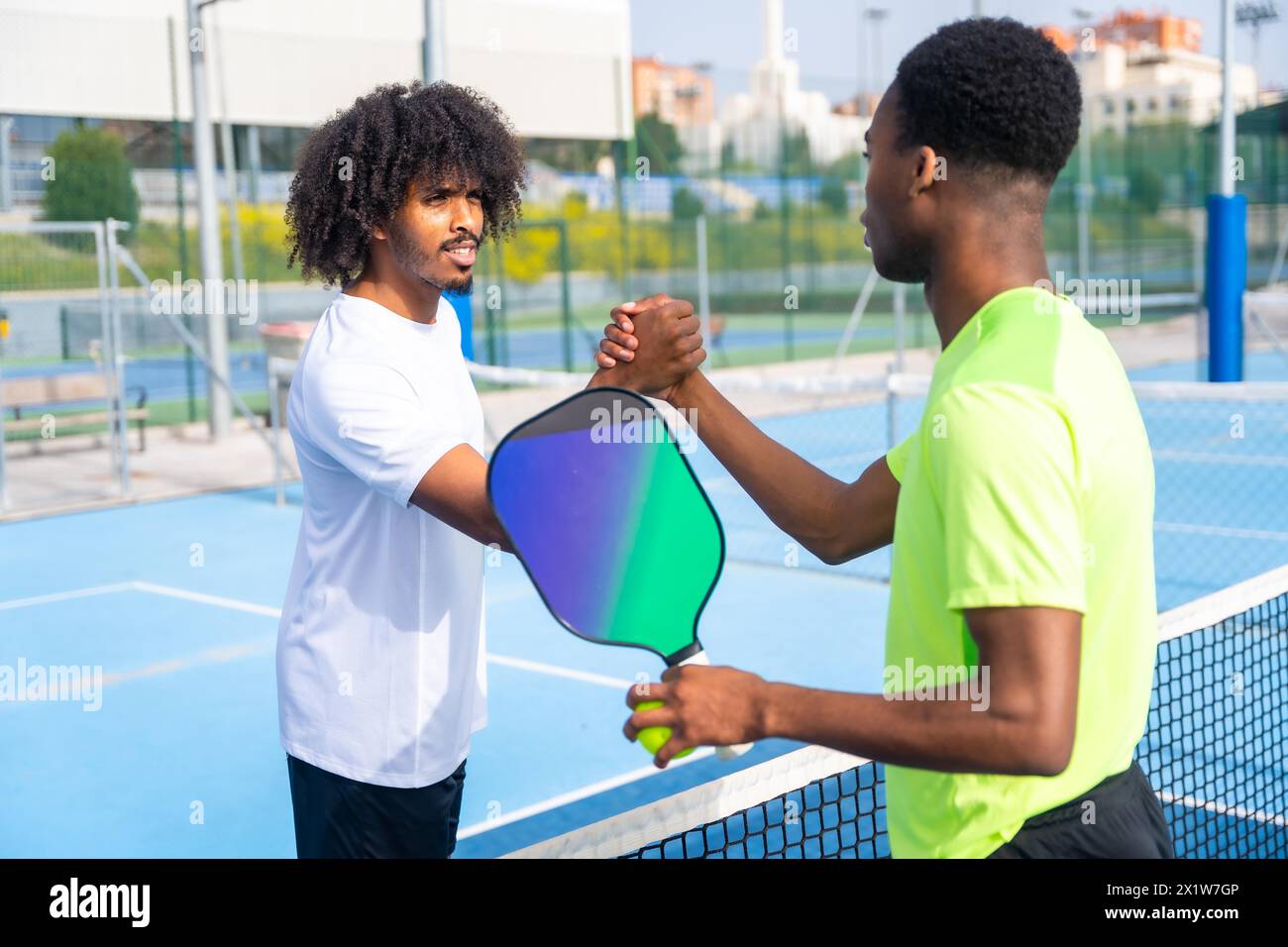 Two african american young men shaking hands before playing pickleball ...