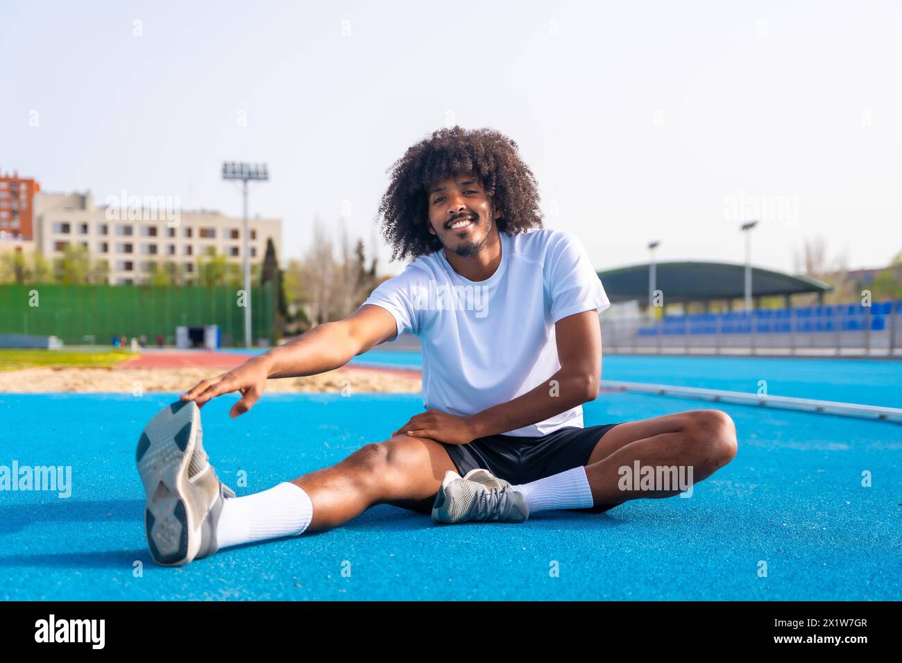 Frontal portrait of an African smiling man with curly hair and sports ...