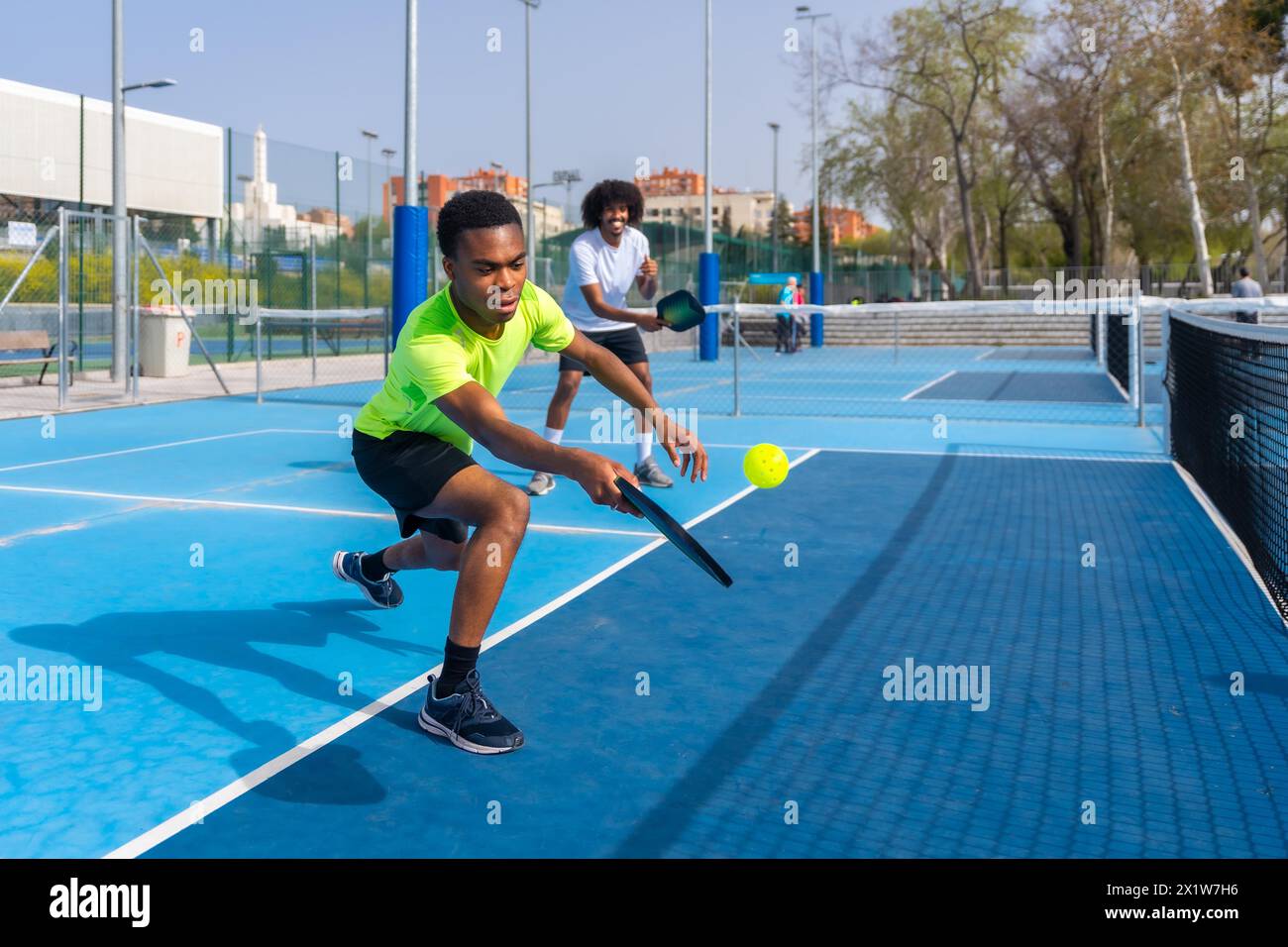 Man running to reach a ball playing pickleball with friend in an ...
