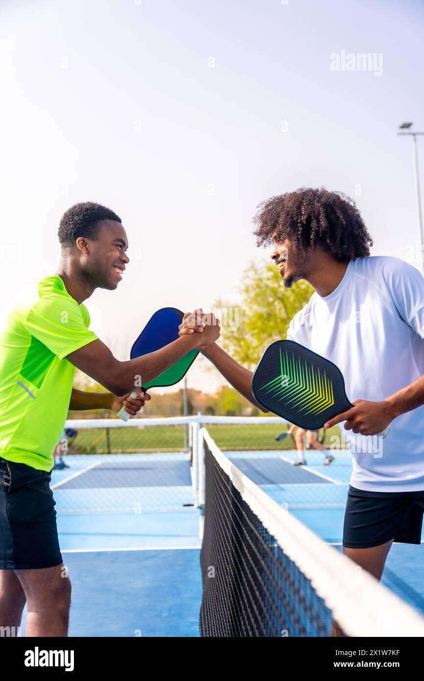 Vertical side view of two african sportive men shaking hands before ...