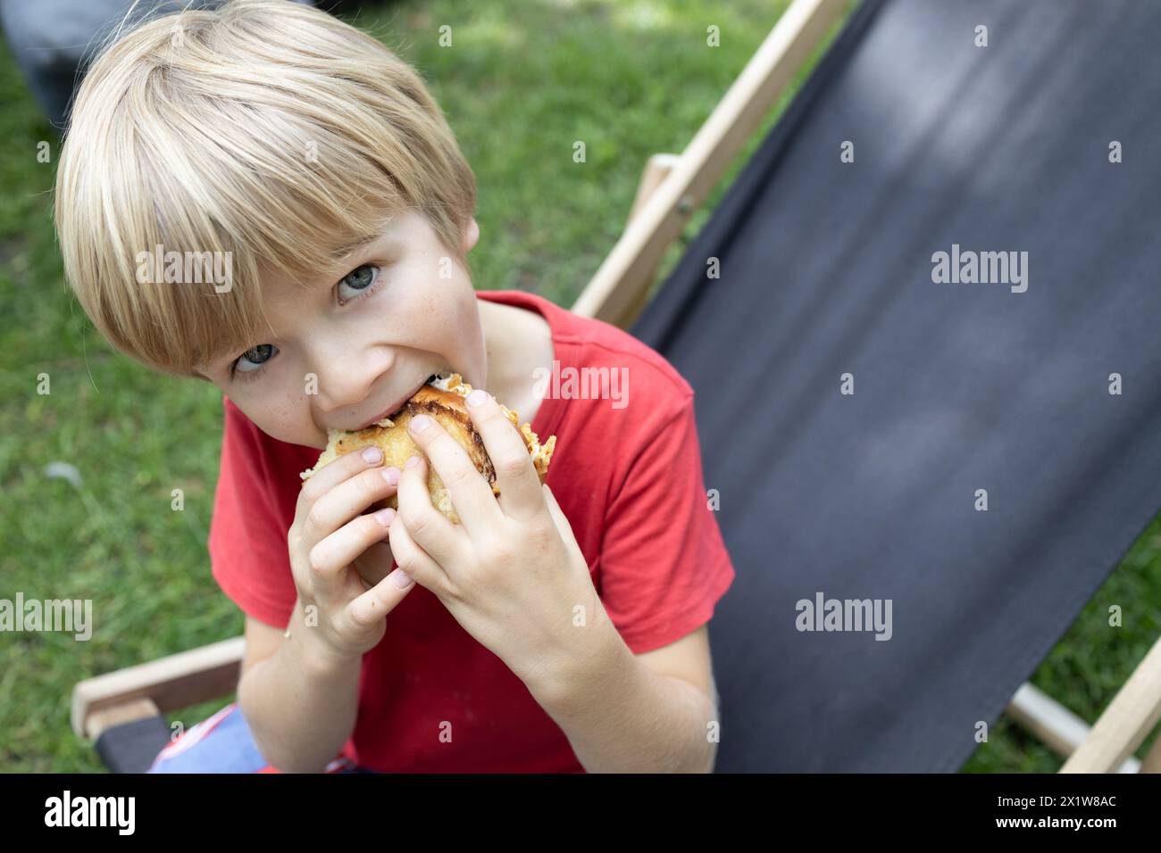 positive boy bites a sandwich during recess outdoors in the park. time ...