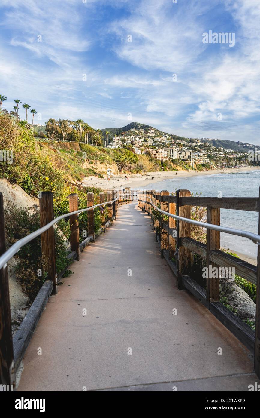 A wooden boardwalk leads to the beach. The boardwalk has a railing ...