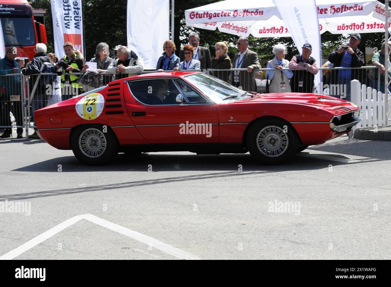 Red classic sports car drives past a crowd at a classic car race ...
