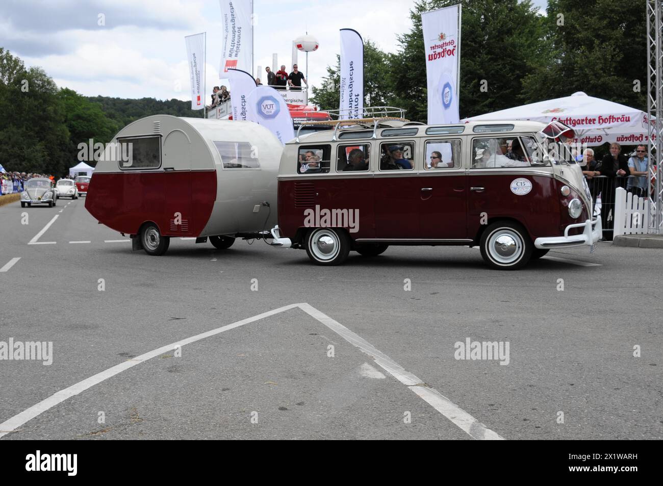 A classic red VW bus with attached caravan at an event, SOLITUDE ...