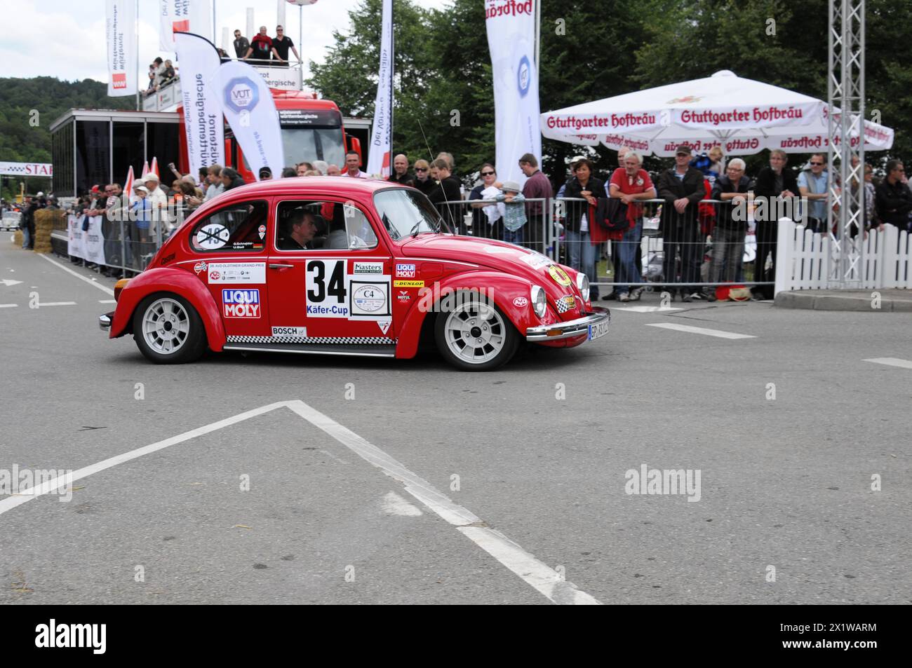 A red Volkswagen Beetle classic car with racing number surrounded by ...