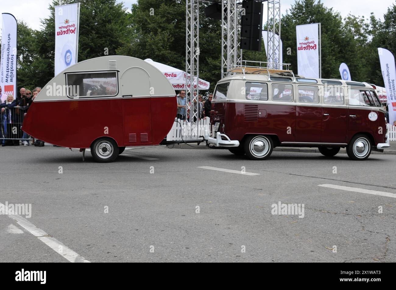 Side view of a VW bus with caravan in front of a crowd of spectators ...