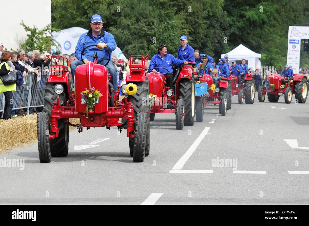 Porsche Diesel tractors, in a parade, driven by people in blue overalls ...