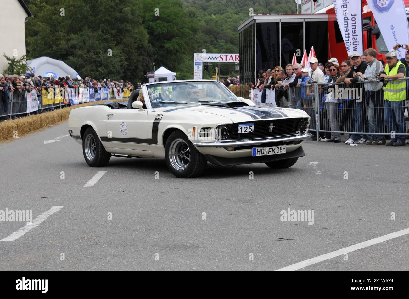 White Ford Mustang convertible at a classic car rally with spectators ...