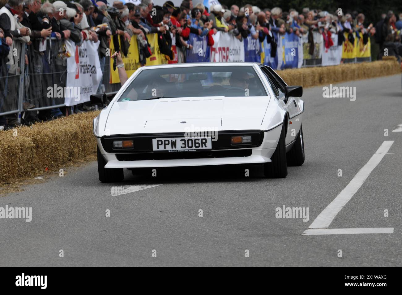 A white sports car drives on a race track, surrounded by spectators ...