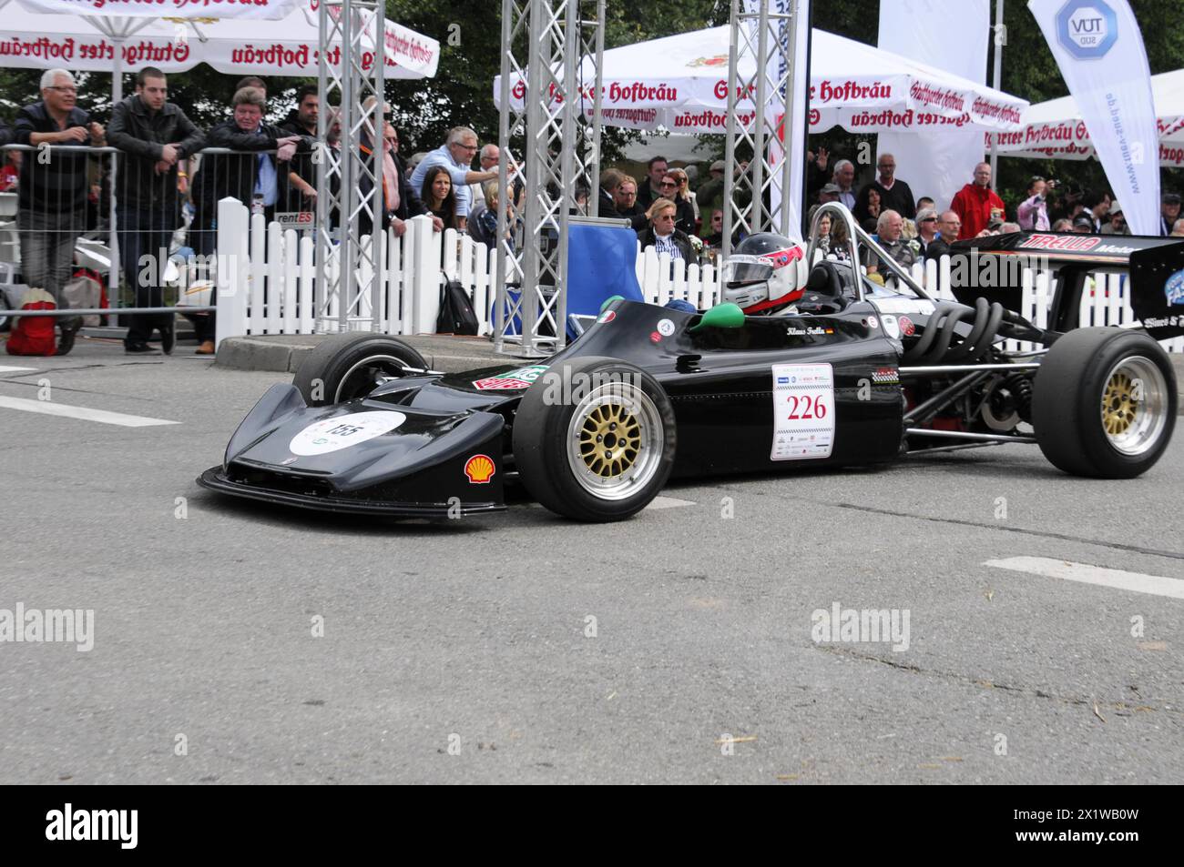 Black racing car with gold-coloured details on a race track, audience ...