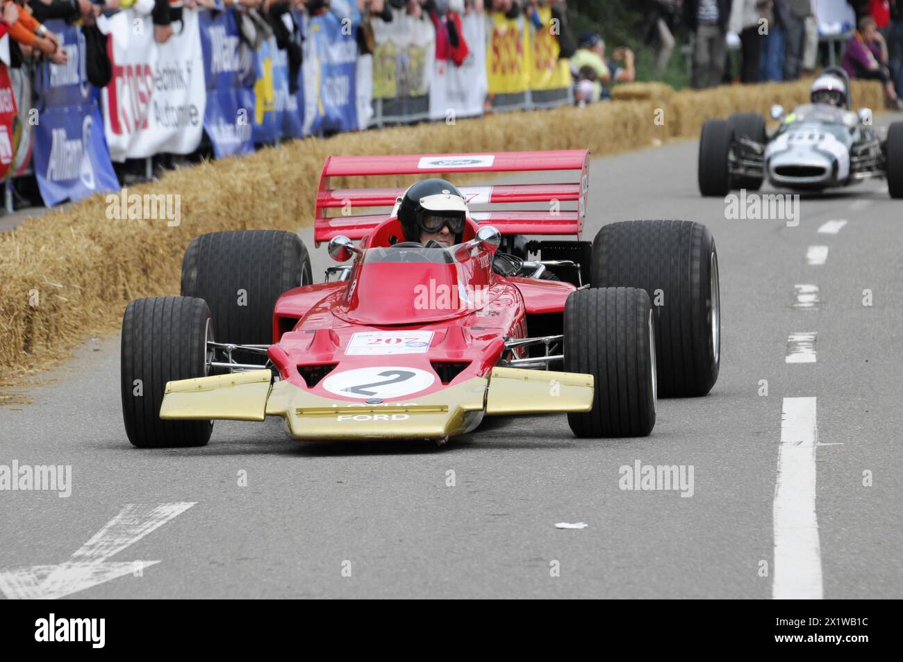 Red formula car in racing action, surrounded by bales of straw and ...