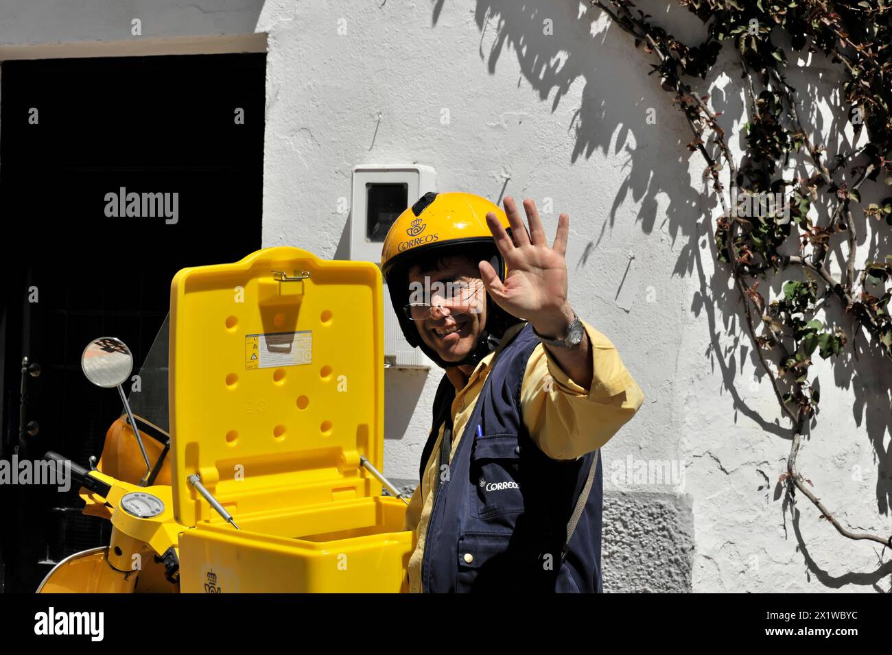 Solabrena, A smiling postman in a yellow uniform greets friendly while ...