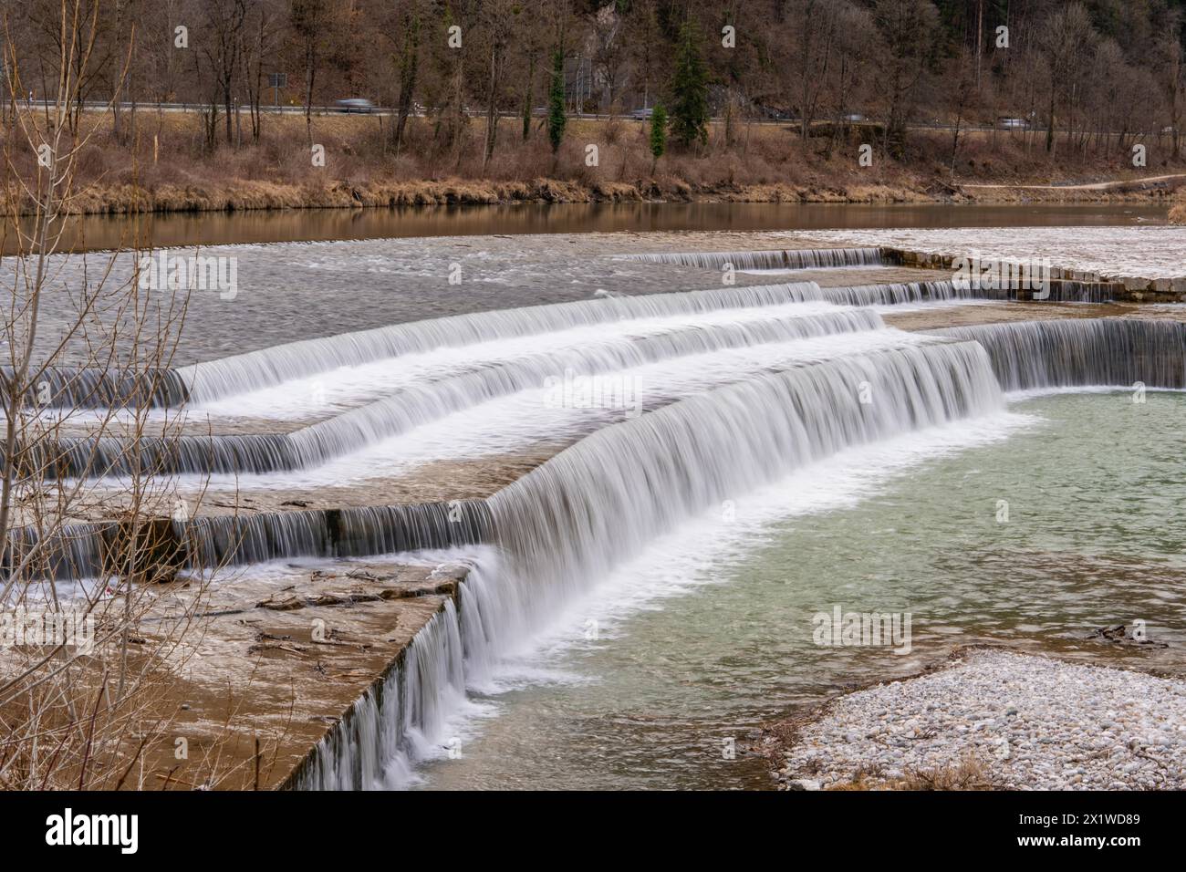 Stepped waterfall flows into a calm river in a wooded landscape, Bad ...
