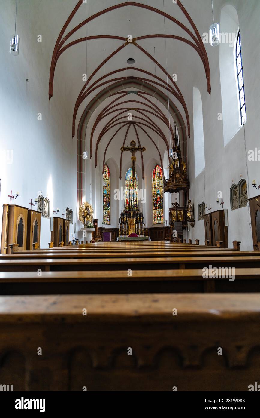 Interior view of a church with wooden pews and coloured stained glass ...