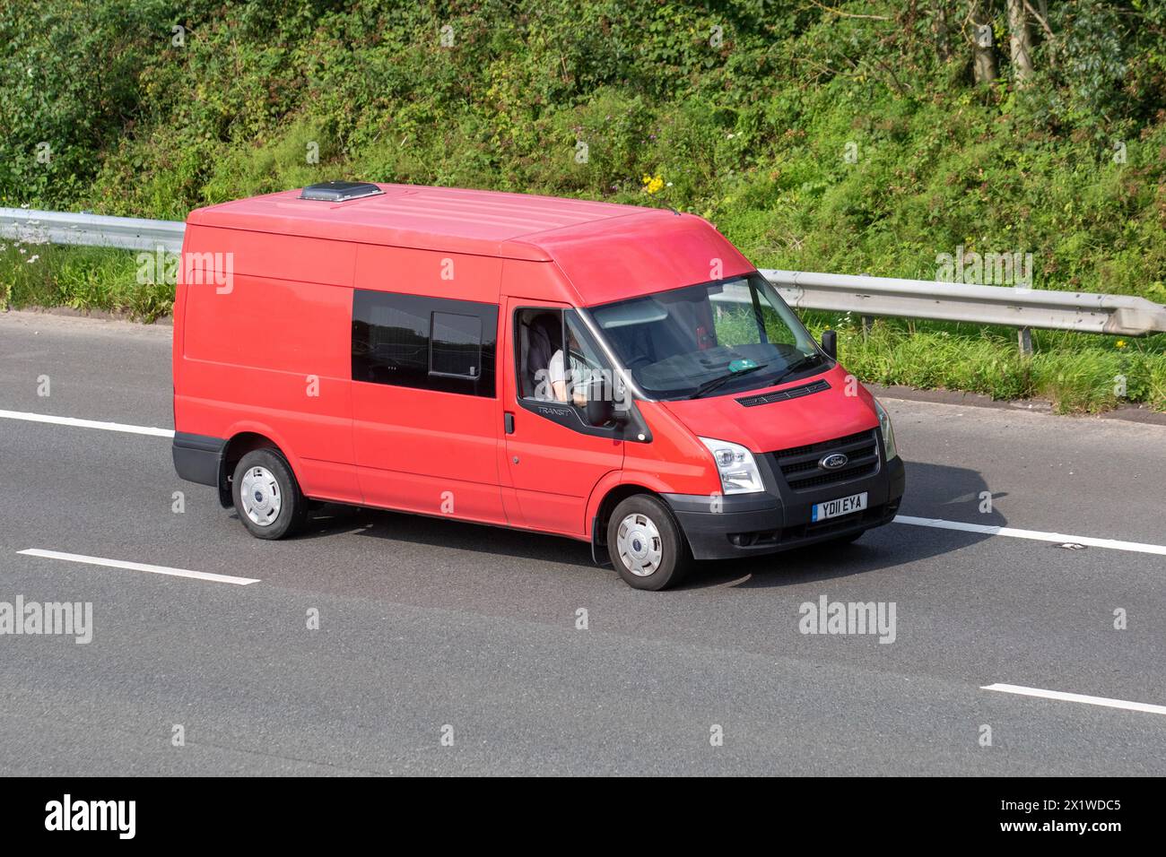 2011 Red Ford Transit 115 T300L FWD window van travelling on the M6 ...