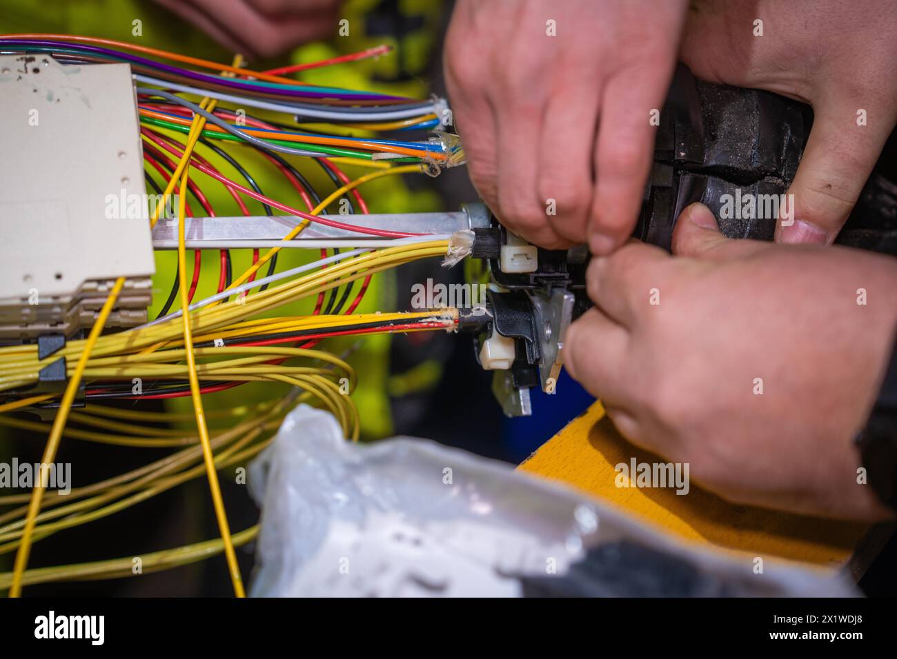 Close-up of an electrician's hands working on a complex wiring harness ...