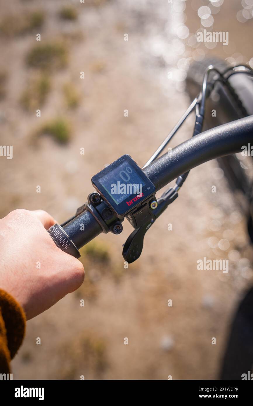 A hand operates a bicycle speedometer on the handlebars of a bicycle ...