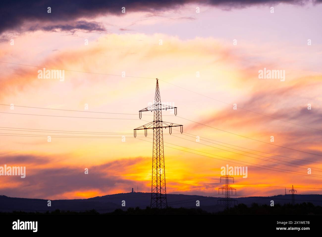 beautiful dramatic landscape, power towers, field in evening in rays of ...