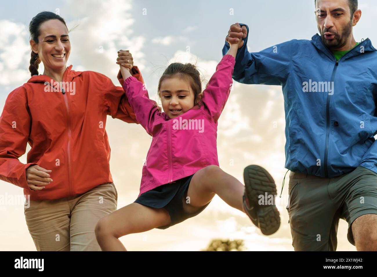 Family outing - child bursts into laughter as her parents lift her into ...