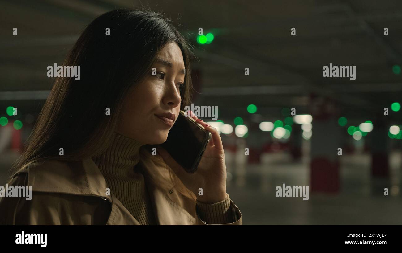 Worried upset Asian woman talk mobile phone in parking call worried ...