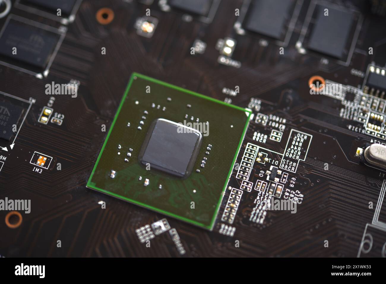 A brown printed circuit board with a processor chip and video memory ...