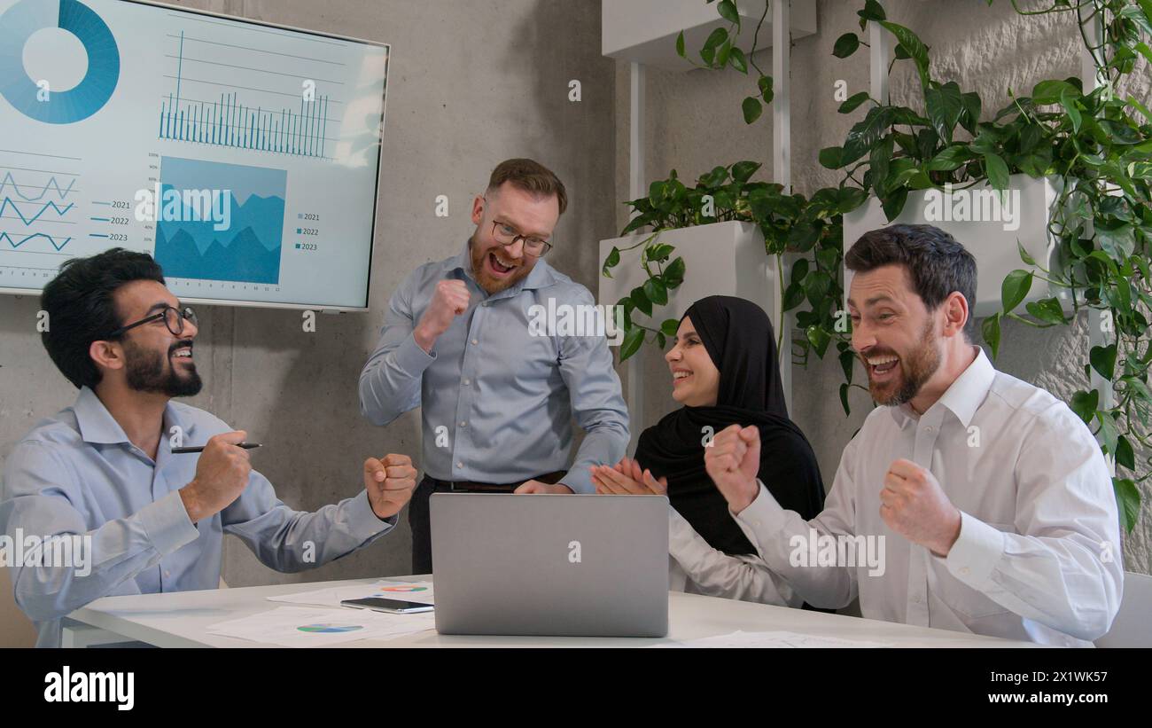 Happy multiethnic business colleagues celebrating laptop win success ...