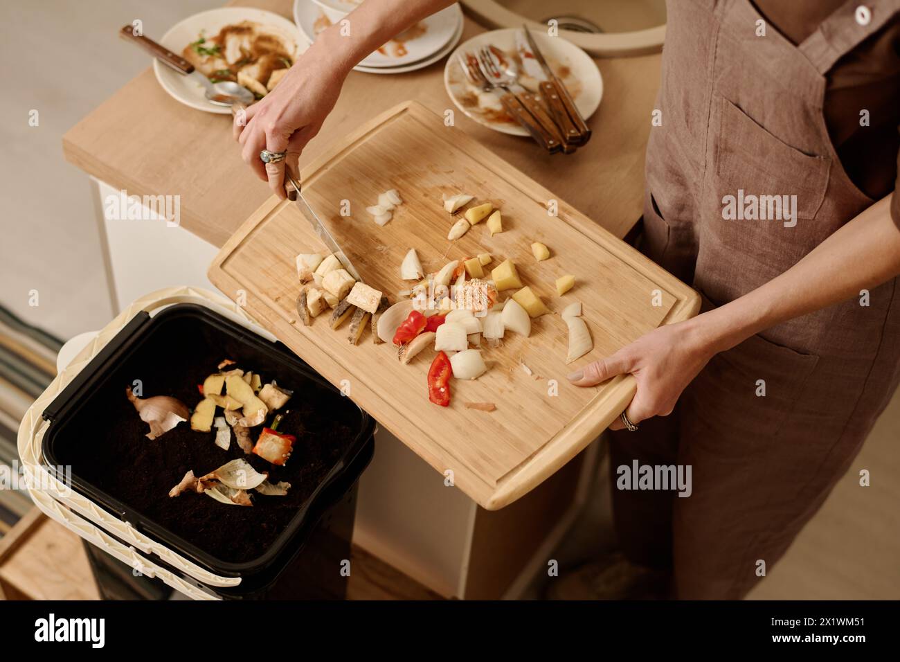 High angle of young unrecognizable woman putting leftover food into bin ...