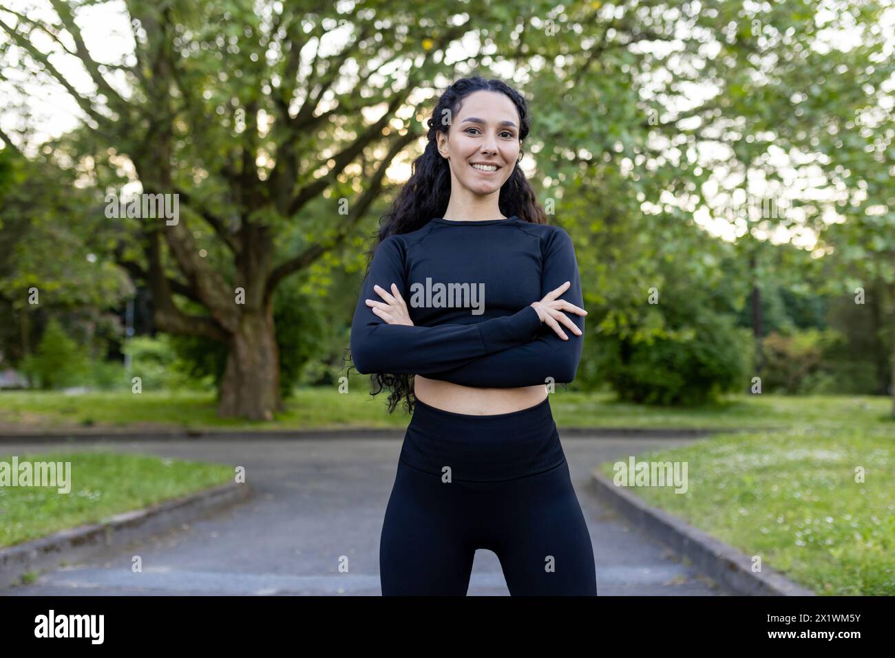 A cheerful Hispanic woman in athletic attire confidently poses with ...