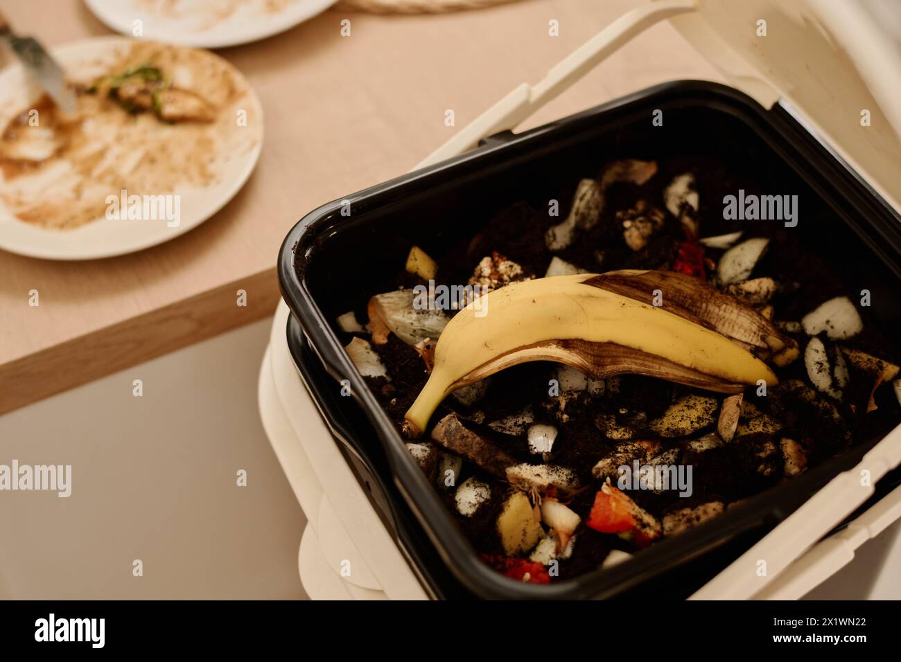 High angle of open trash bin with banana peel lying on top of heap of ...