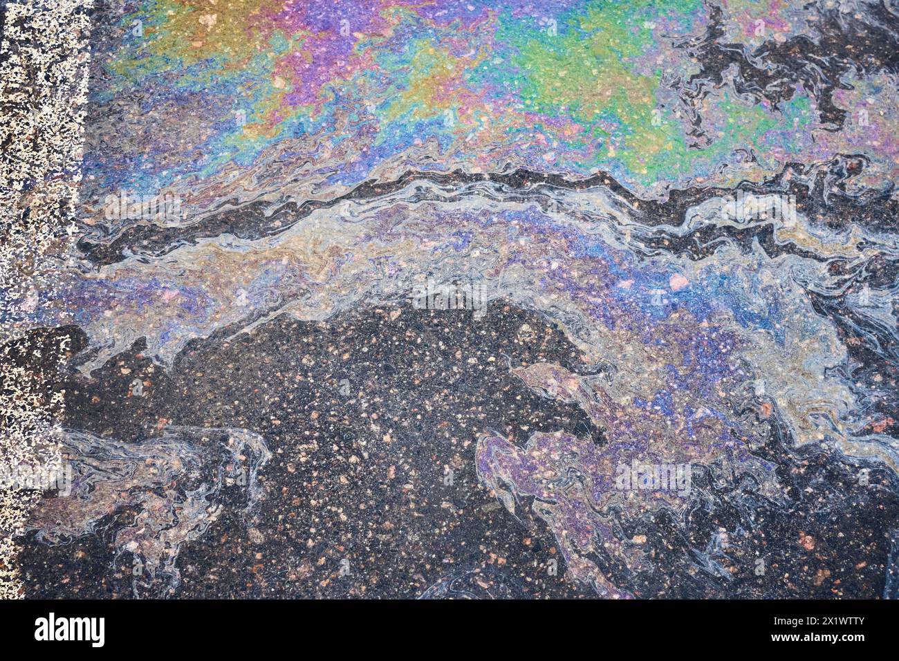 A car's oil and gas stains mark the surface of the parking asphalt ...