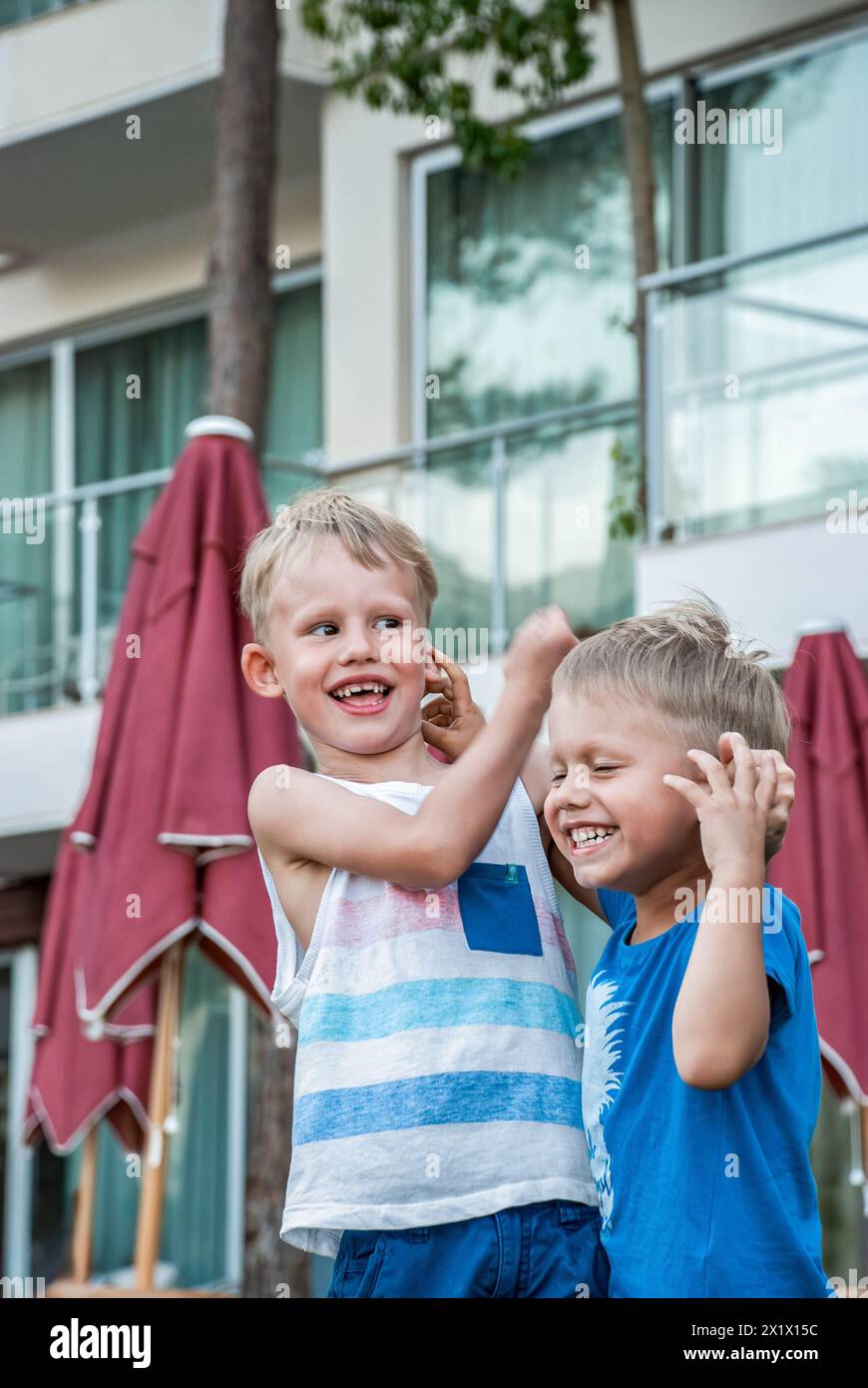 Two little boys are laughing and playfully pulling each others ears on ...
