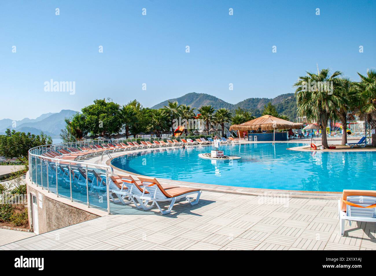 Circular swimming pool surrounded by lounge chairs and a bar with a ...