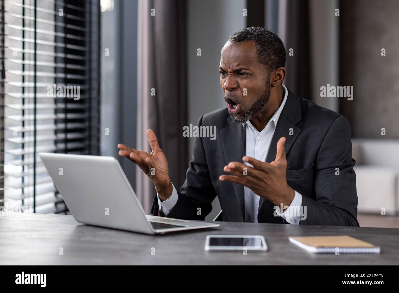 Aggressive black man screaming in despair while working by laptop in ...