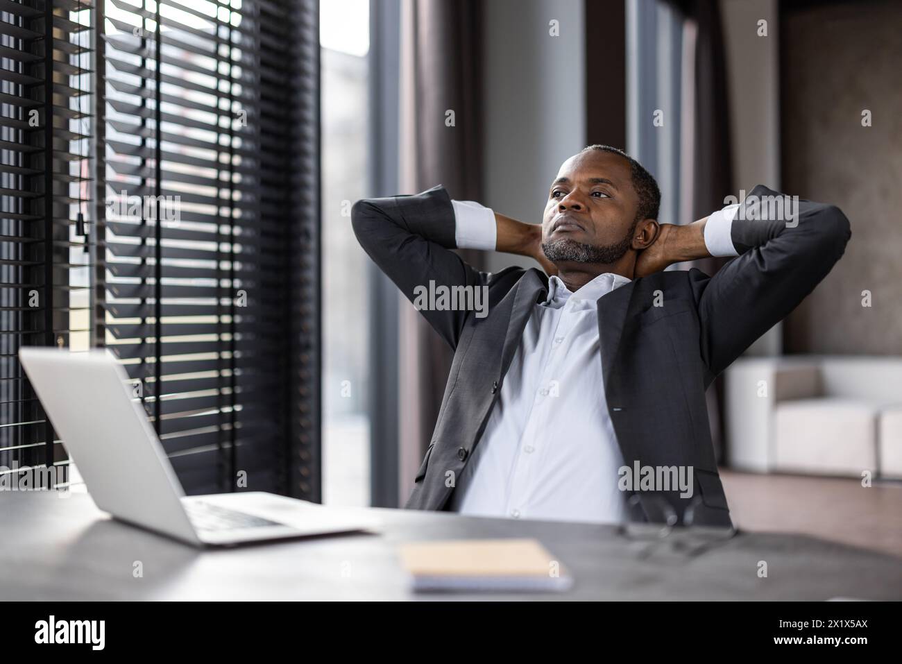 Overloaded black man in formal outfit leaning on back of chair while ...