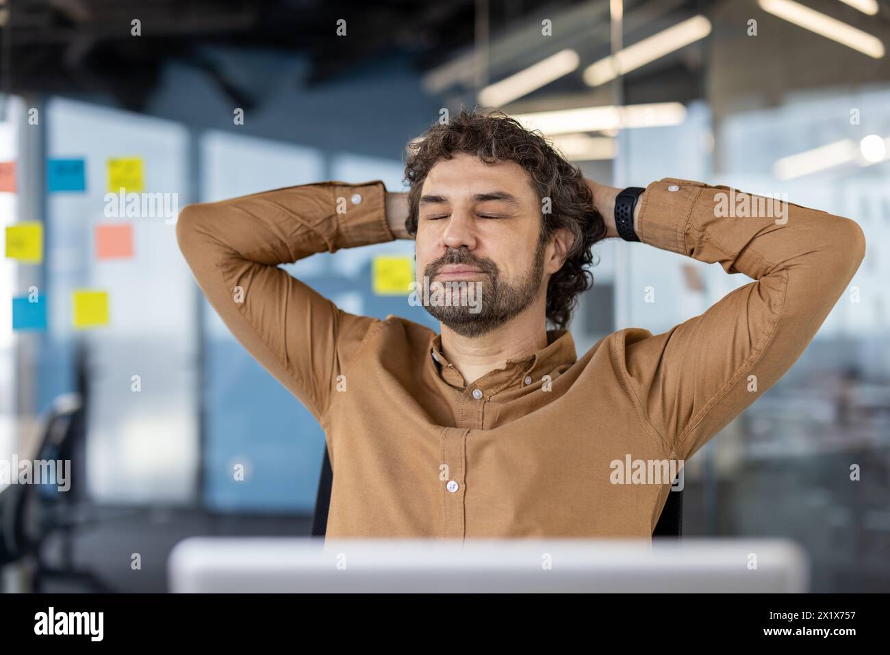Calm caucasian guy sitting on chair with hands behind head and closed ...
