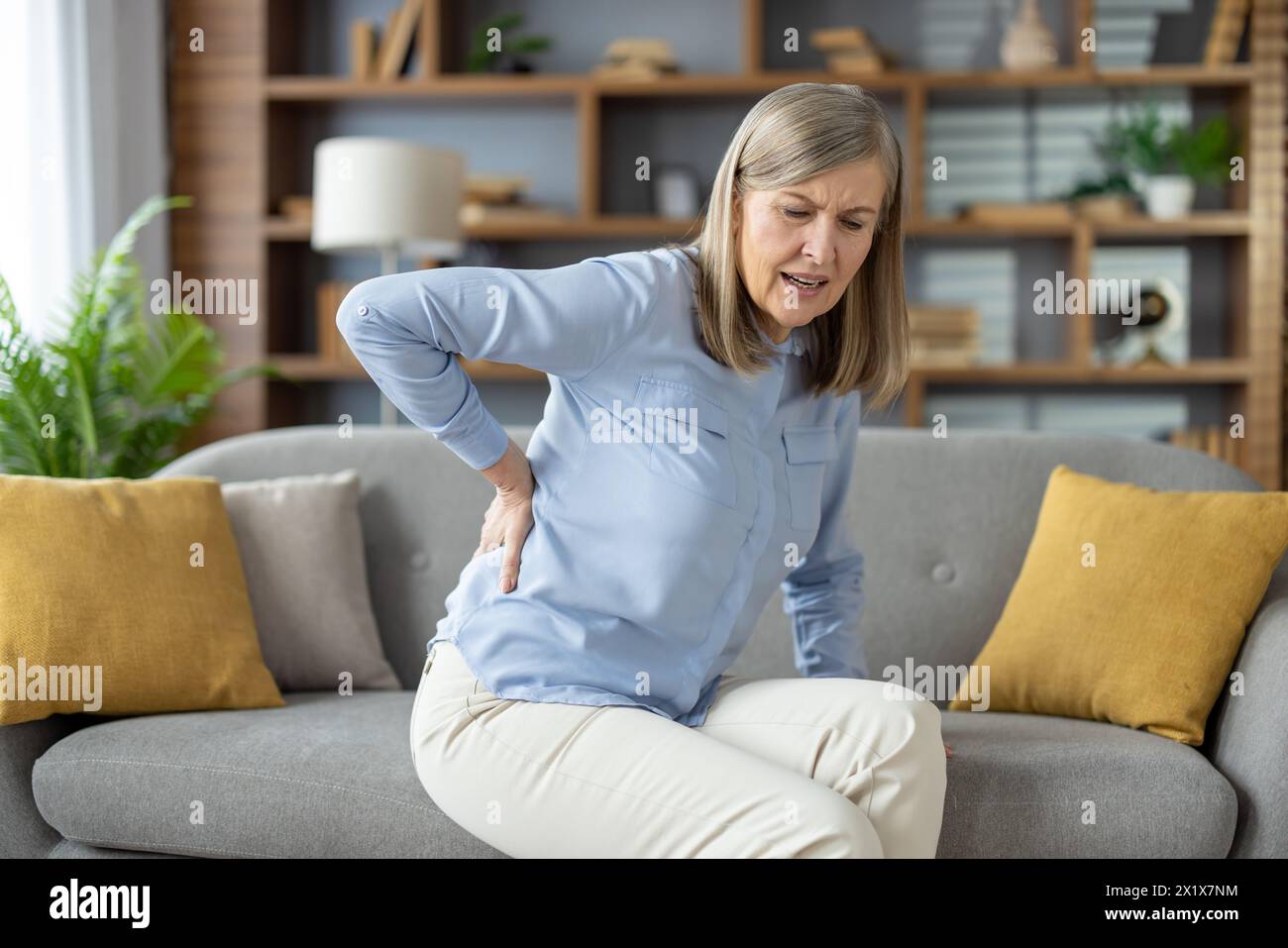 Unhealthy mature woman keeping hand on back while struggling with pain ...