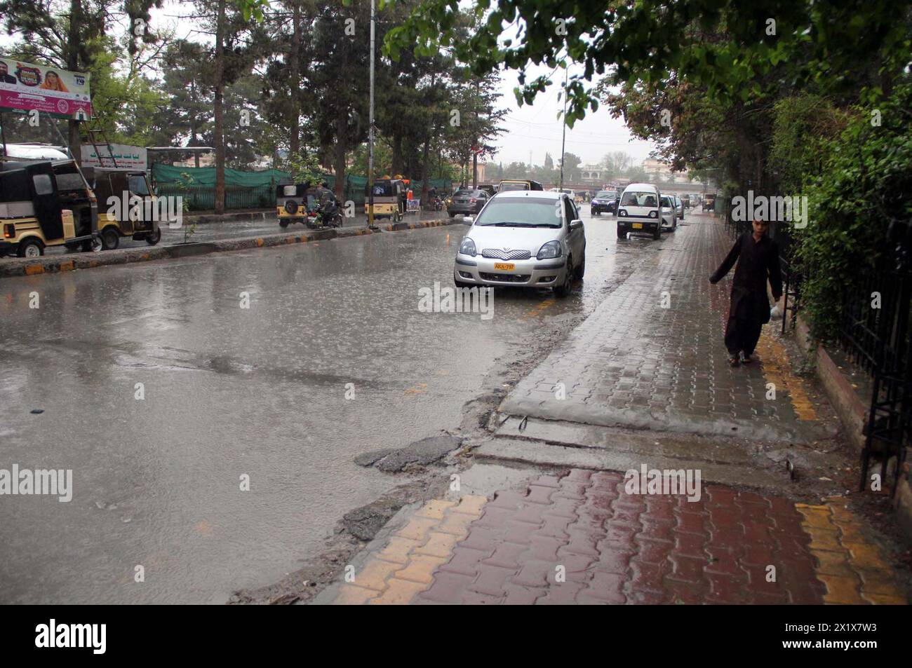 Commuters make their way to a road amid heavy rains in Quetta on ...