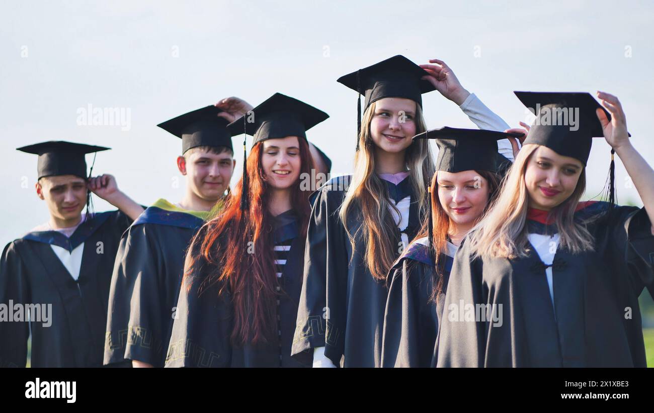 Cheerful graduates pose with raised diplomas on a sunny day Stock Photo ...