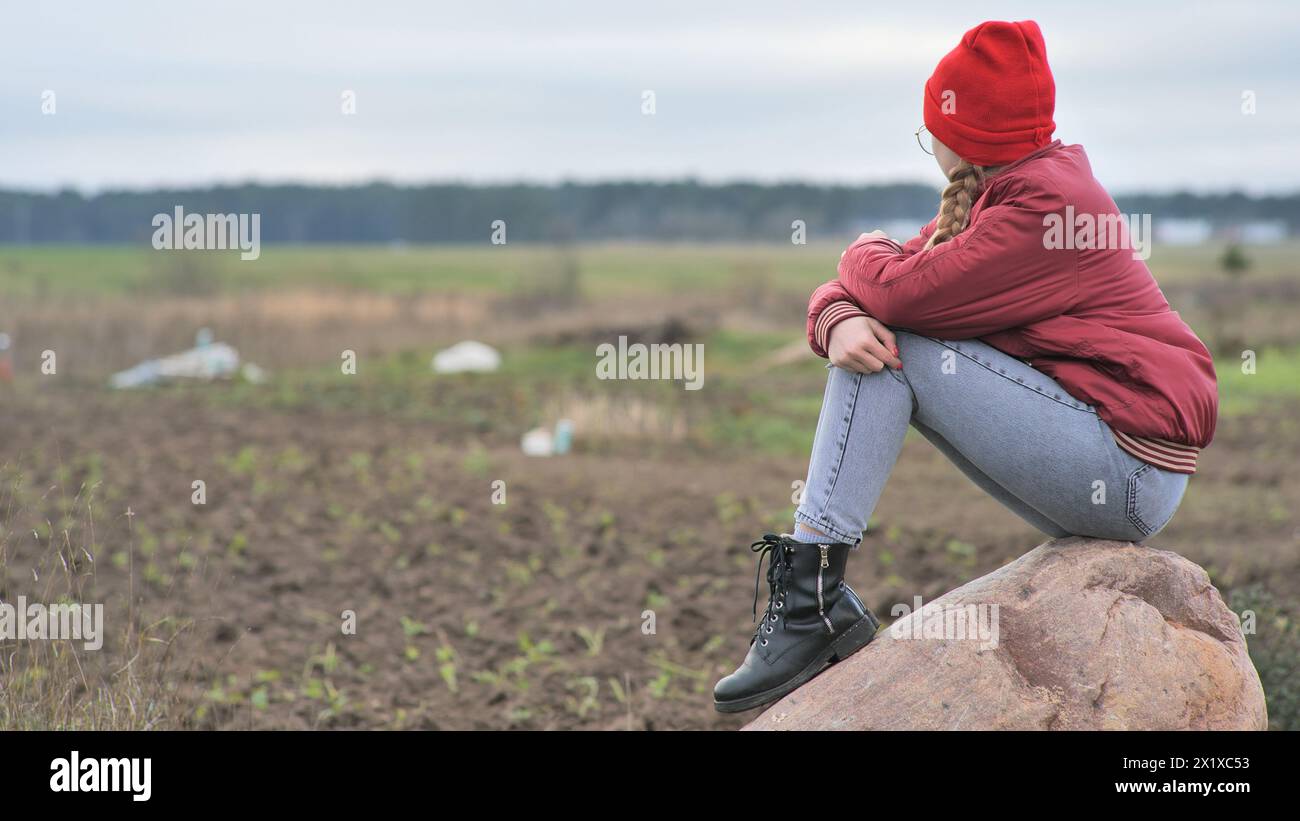 A sad teenage girl sits on a rock in a field and cries Stock Photo - Alamy