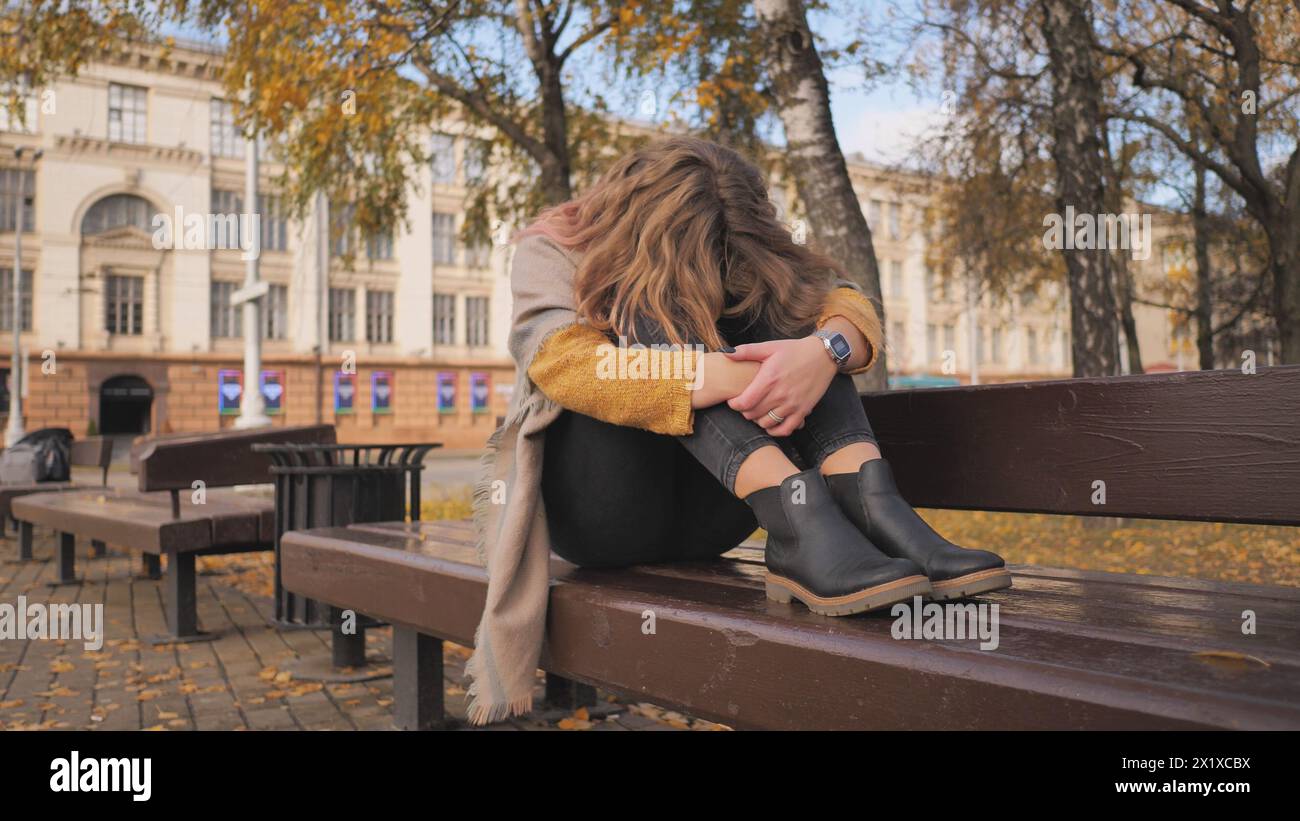 A young girl crying on a park bench in the fall Stock Photo - Alamy