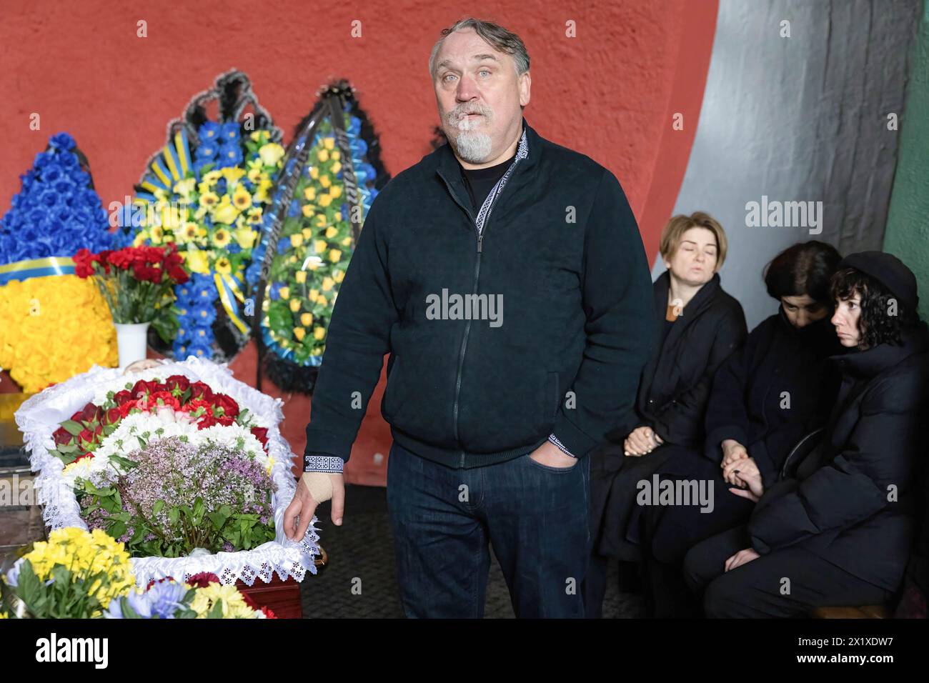 A twin brother of the deceased stands near the coffin with the body ...