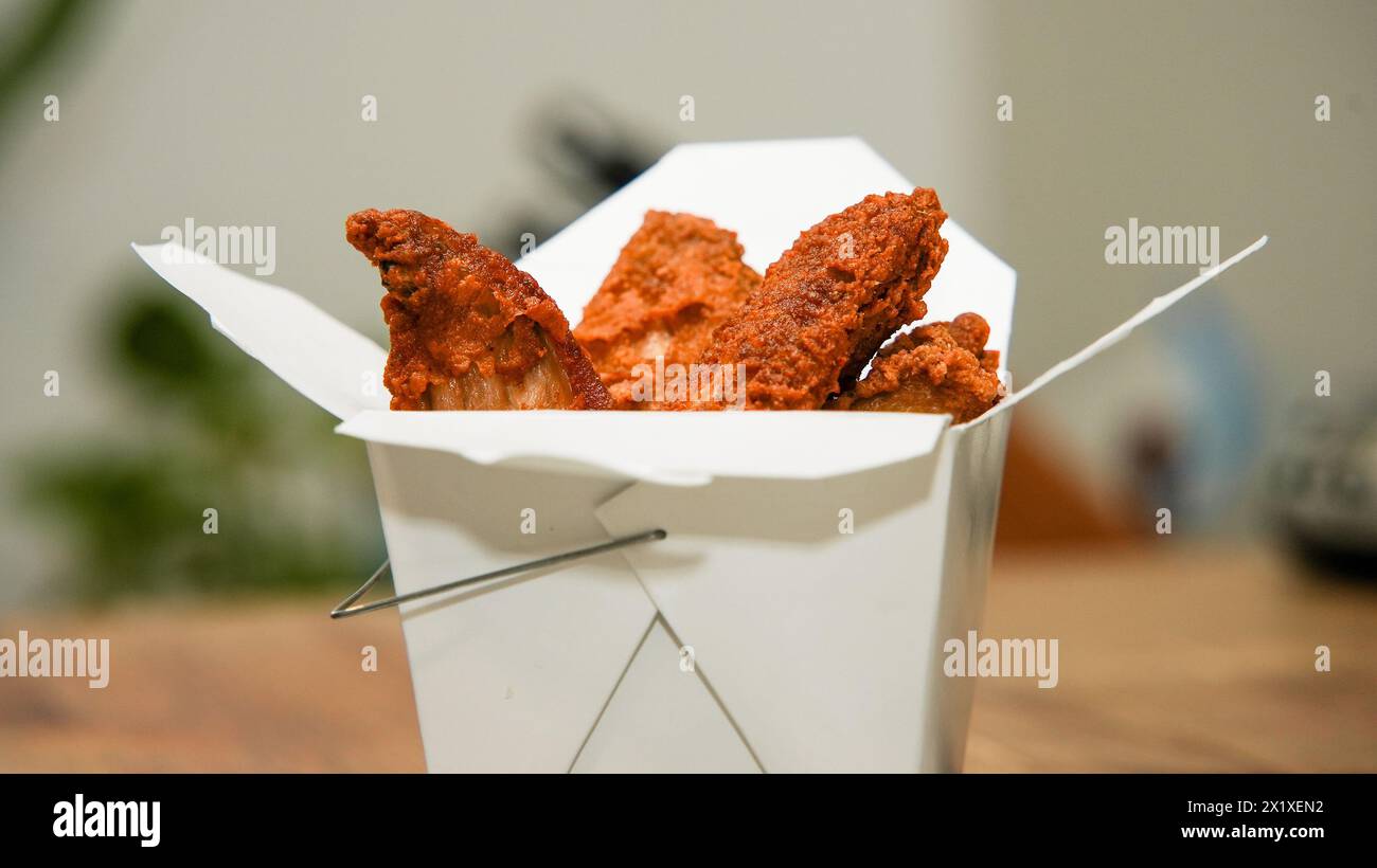 A box of golden-brown fried chicken strips is placed on a kitchen ...