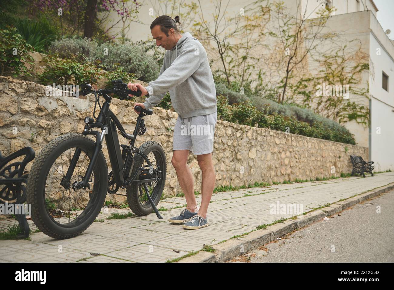 Young male cyclist on sports clothes, pushing his bike while walking ...