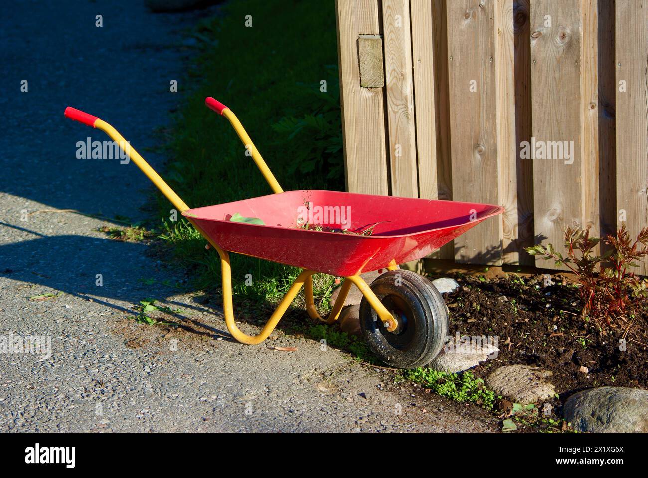 Childrens red common wheelbarrow to be used outdoors for playing and ...