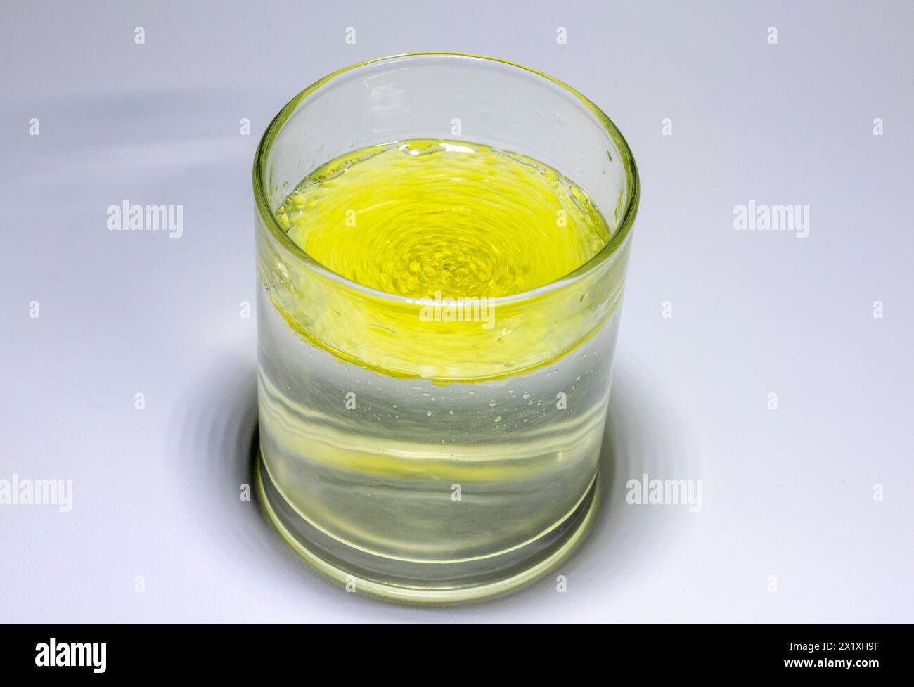 Oil mixed in a glass with water showing that the water and oil separate ...