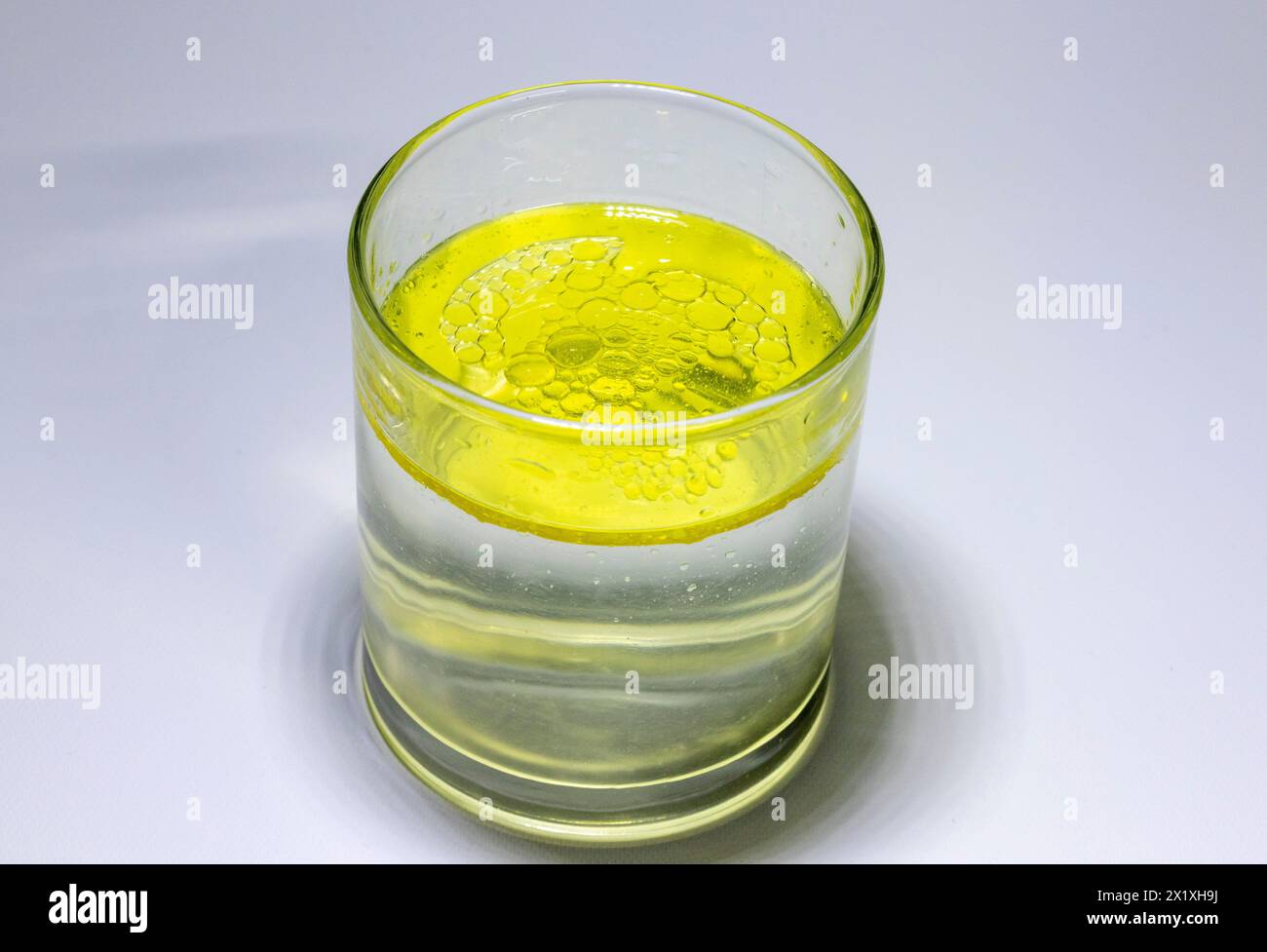 Oil mixed in a glass with water showing that the water and oil separate ...